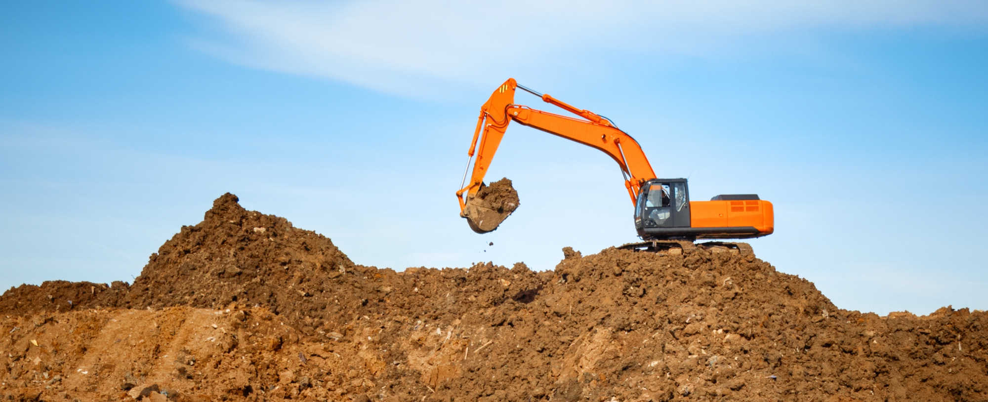 Excavator digs the earth on a background of blue sky - Rock Blaster Hammers